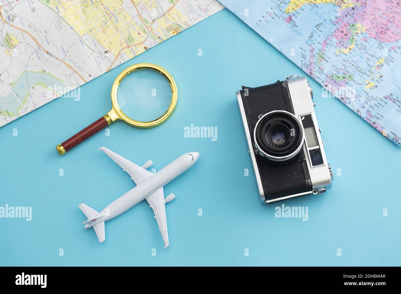 A top view of a camera, airplane toy and magnifying glass on a blue ...