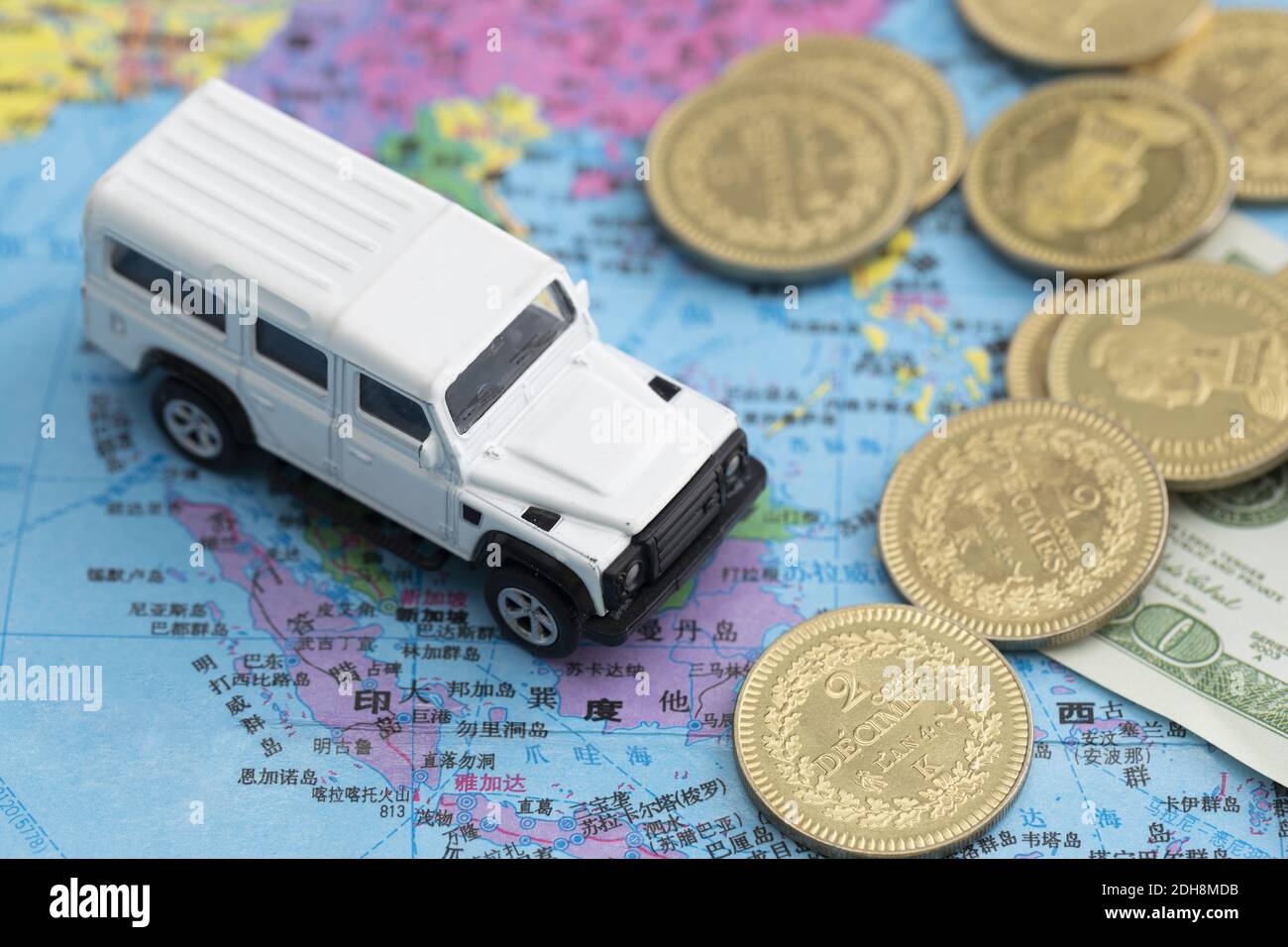 A top view closeup of a toy car, with coins and banknotes on a map ...