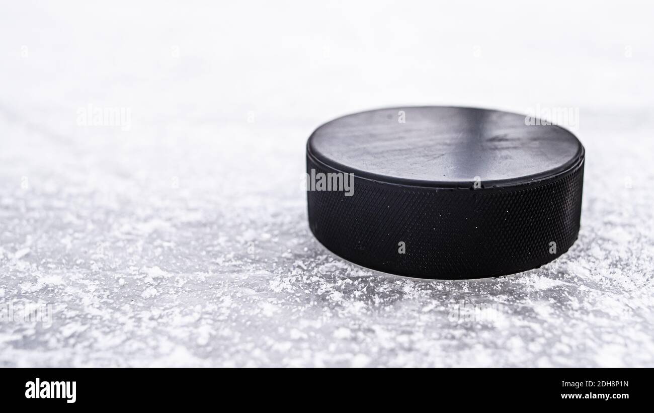 black hockey puck lies on ice at stadium Stock Photo - Alamy