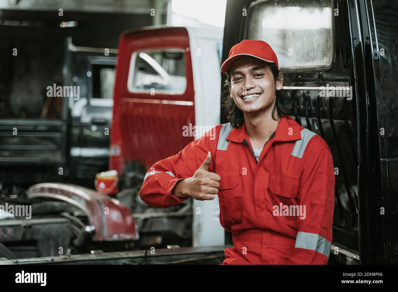 portrait of a young man working as an auto mechanic in a garage showing ...