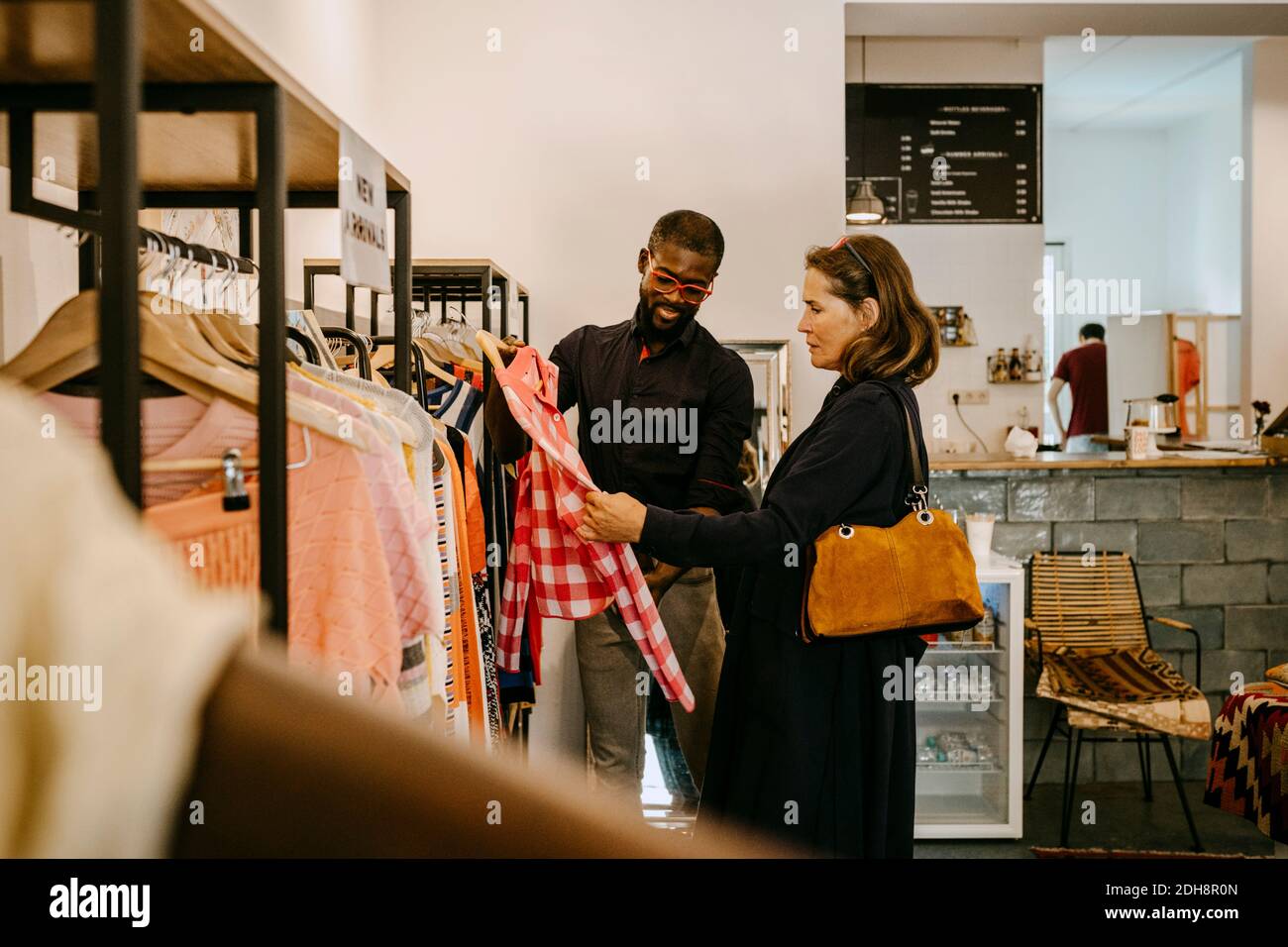 Smiling owner showing clothing to customer in shop Stock Photo - Alamy