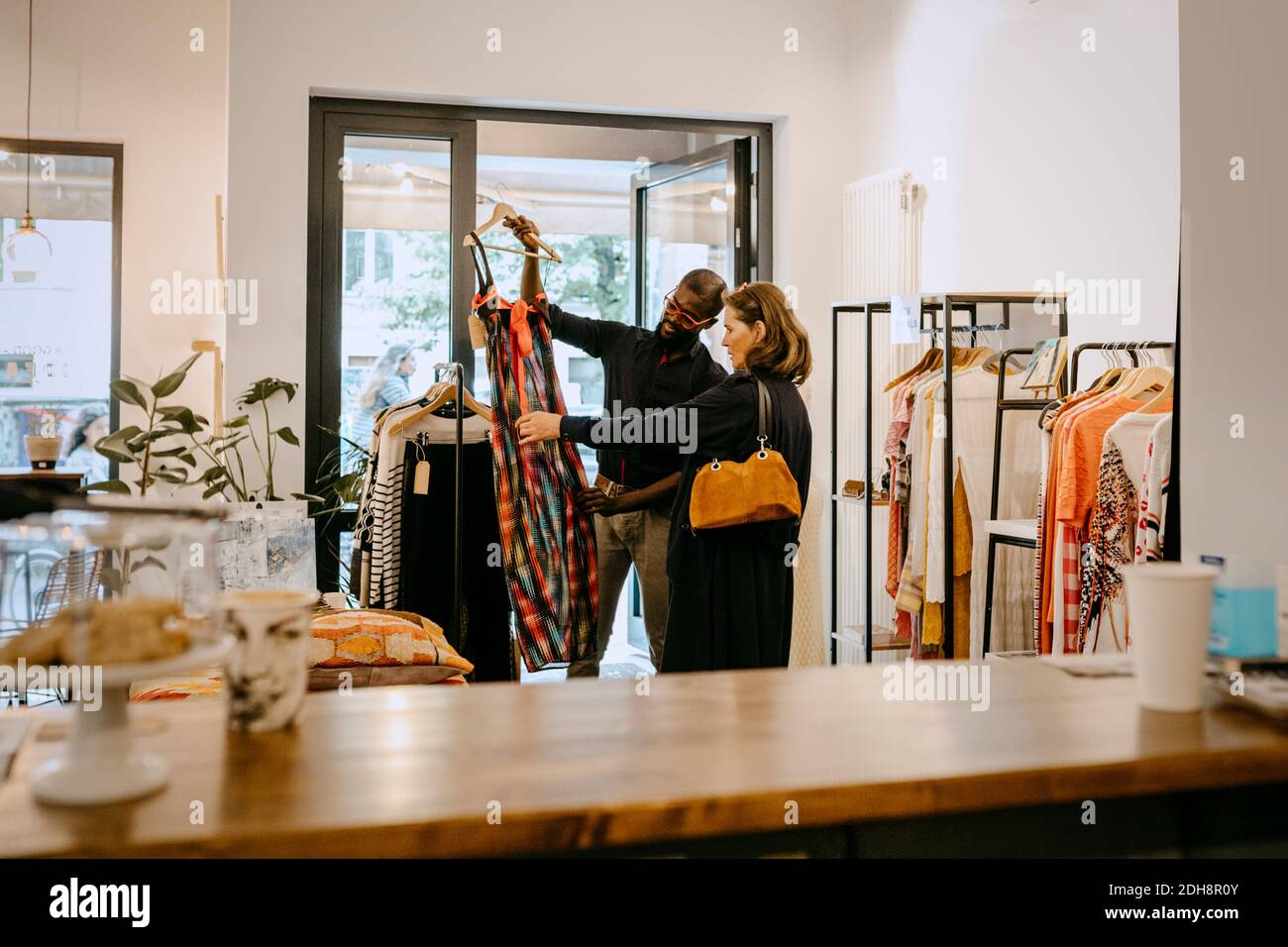 Male owner showing clothing to customer in store Stock Photo - Alamy