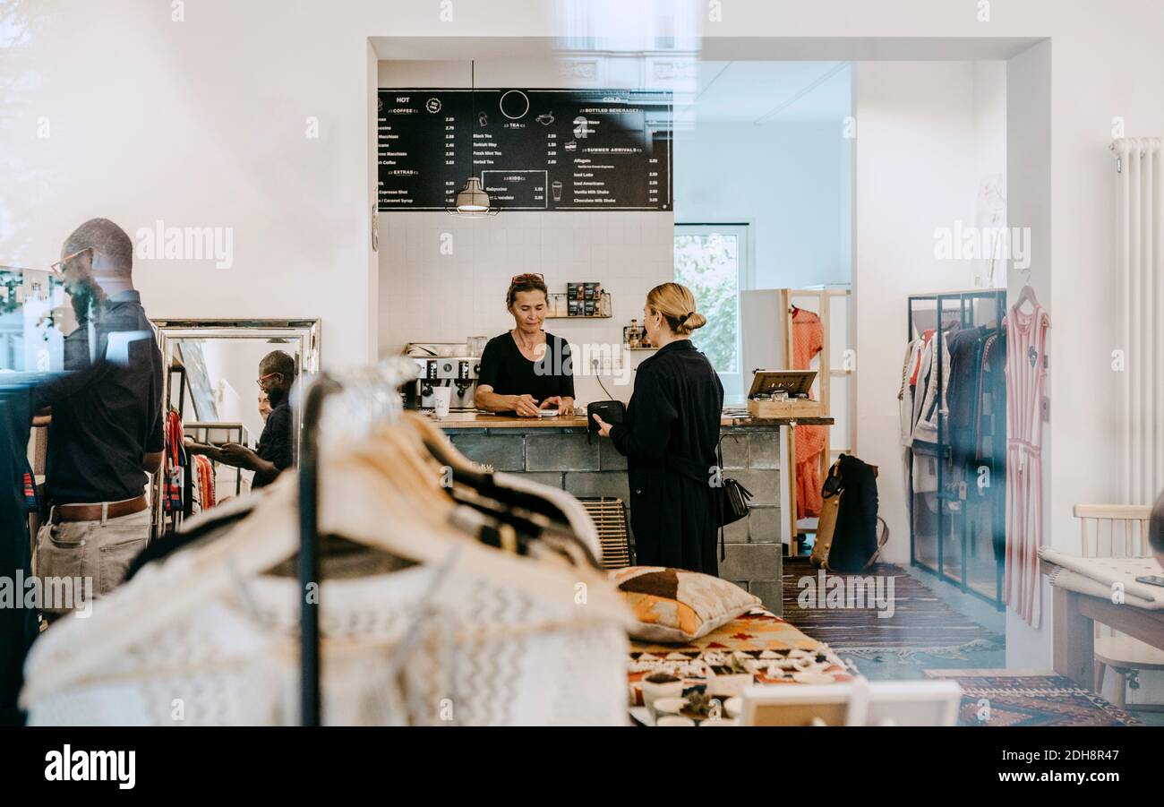 Senior owner talking to female customer in coffee shop Stock Photo - Alamy
