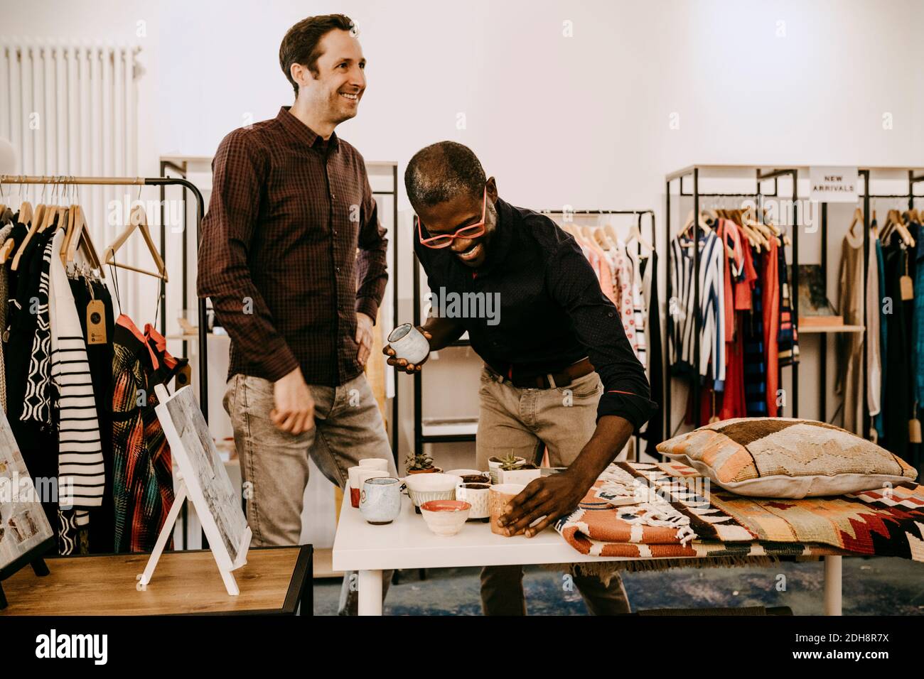 Smiling male owner with employee working in clothing store Stock Photo ...