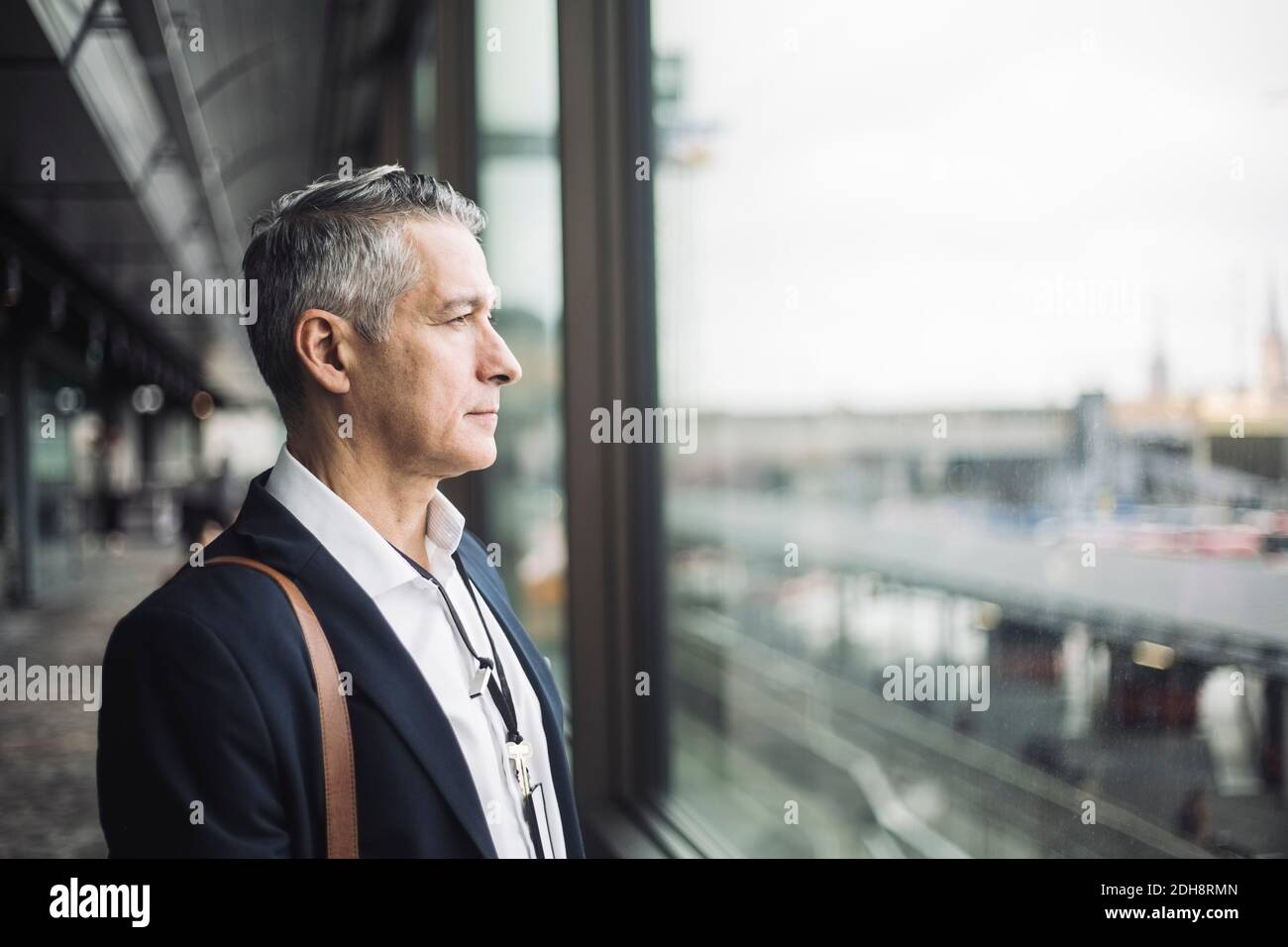 Contemplating entrepreneur looking through window in office Stock Photo ...
