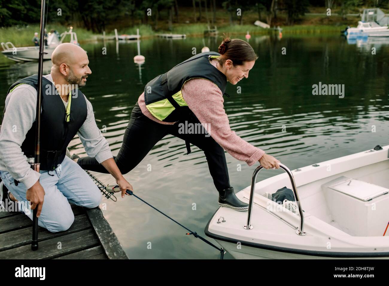 Man holding anchor while female partner getting into boat at lake Stock ...