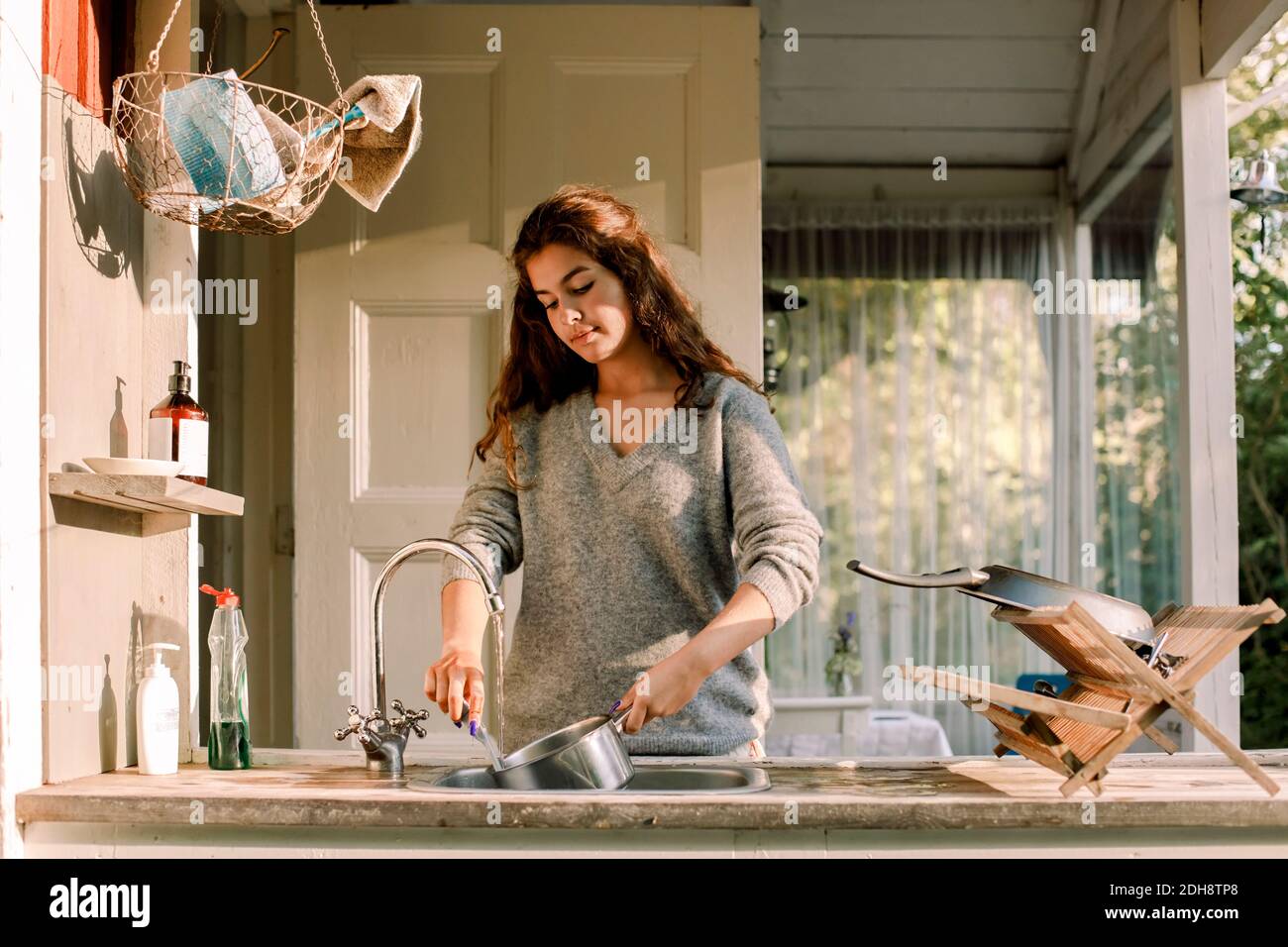 Teenage girl washing utensil in sink outside house Stock Photo - Alamy