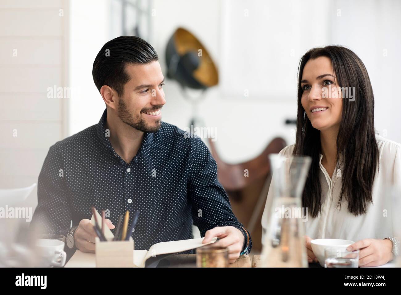 Smiling business people talking during meeting at table in office Stock ...