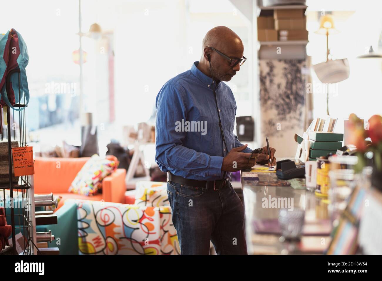 Senior customer writing notes while using technology in store Stock ...