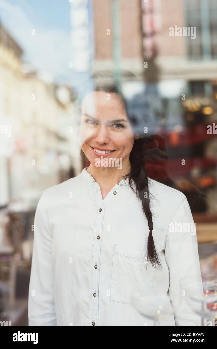 Portrait of smiling female customer seen through glass window Stock ...