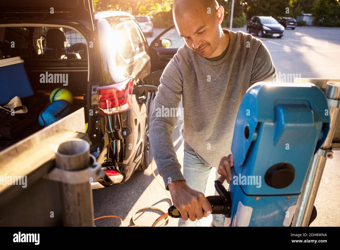 Mature man plugging cable at electric station Stock Photo - Alamy