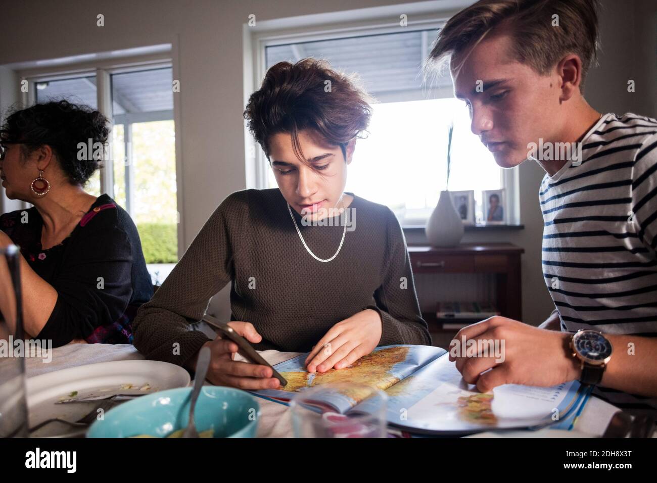Friends reading map while using phone at dining table in dinner party ...