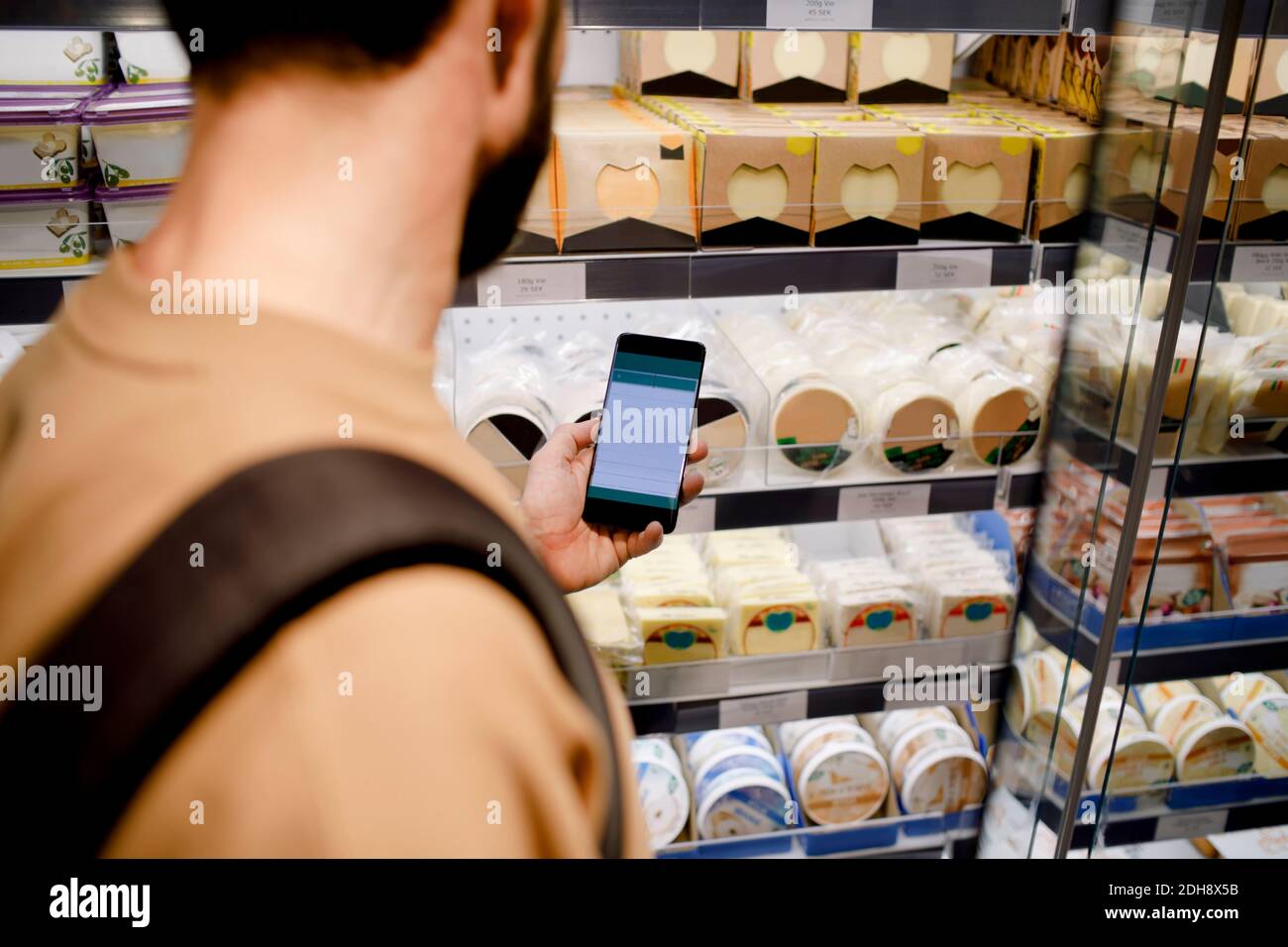 Midsection of customer using mobile phone while shopping in supermarket ...