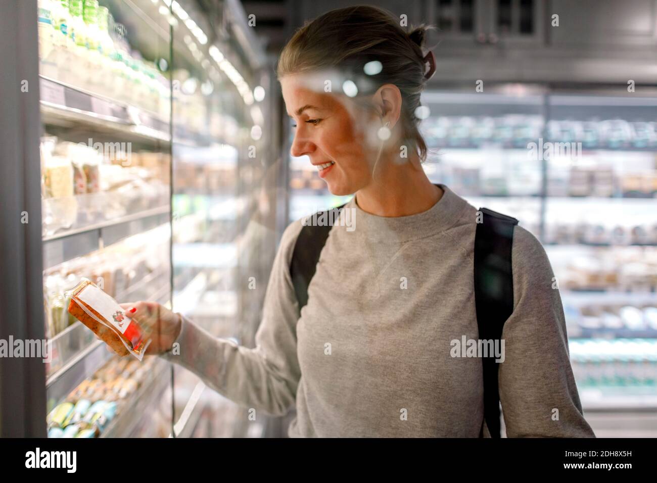 Smiling female customer reading ingredient while shopping in ...