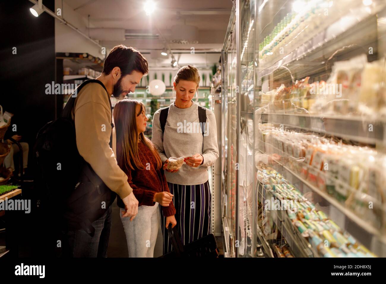 Woman reading ingredient while standing by family in supermarket Stock ...