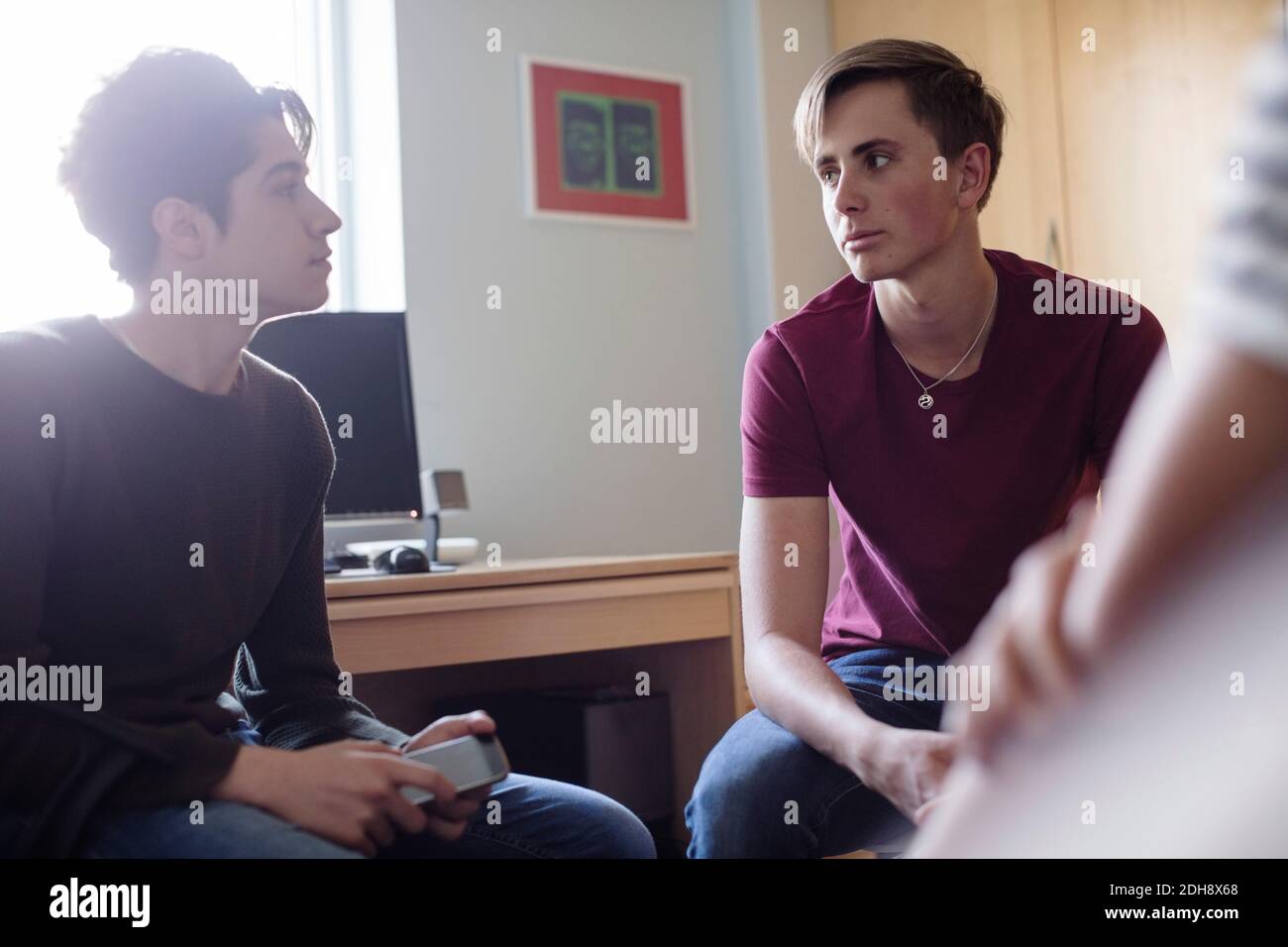 Teenager looking at friend sitting in brightly lit bedroom Stock Photo ...