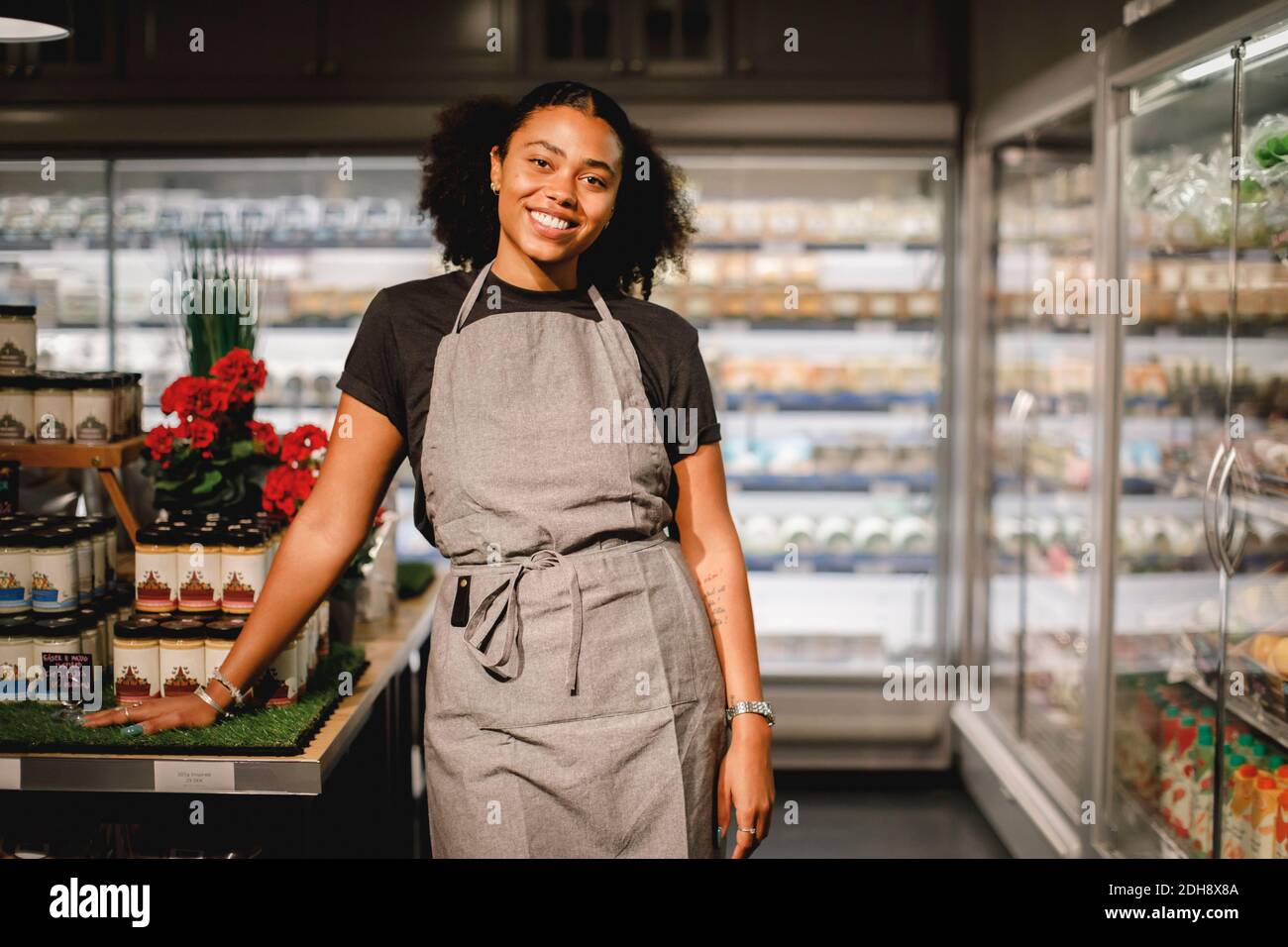 Portrait of smiling saleswoman standing in grocery store Stock Photo ...