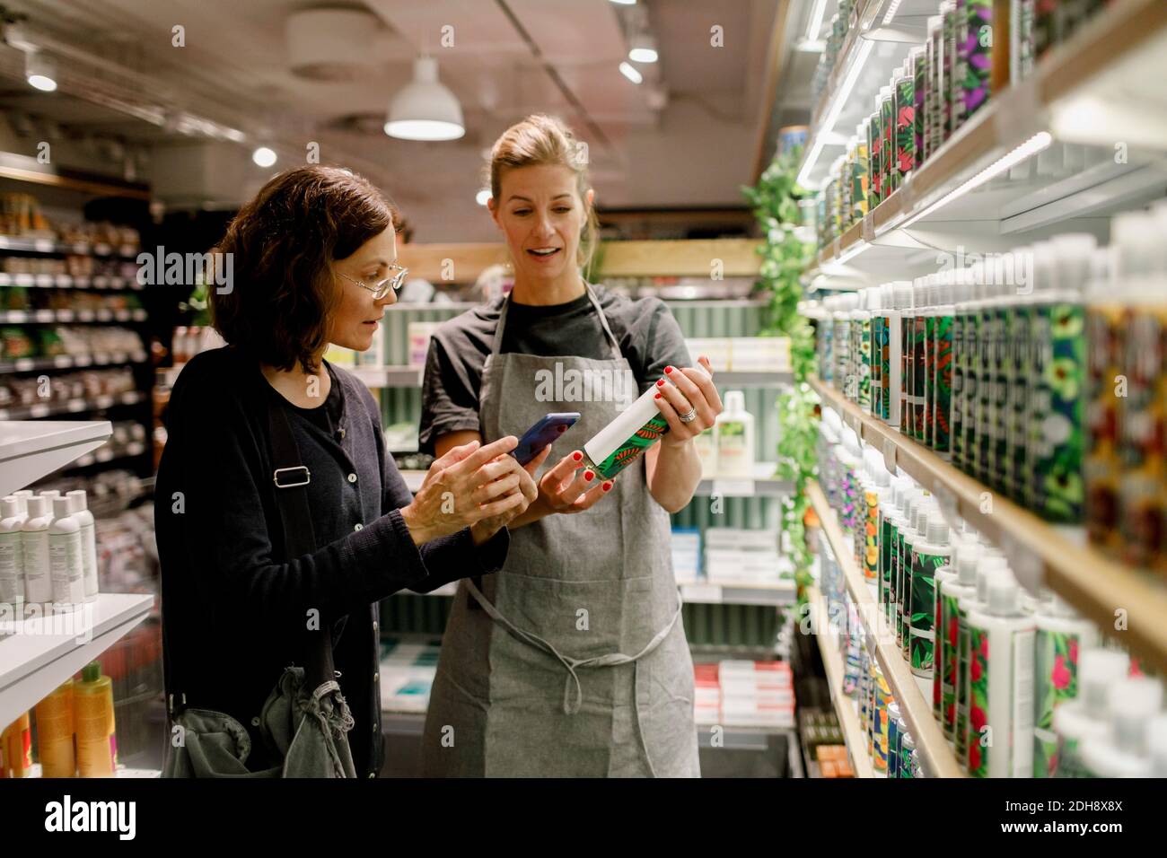 Saleswoman assisting female customer in supermarket Stock Photo - Alamy