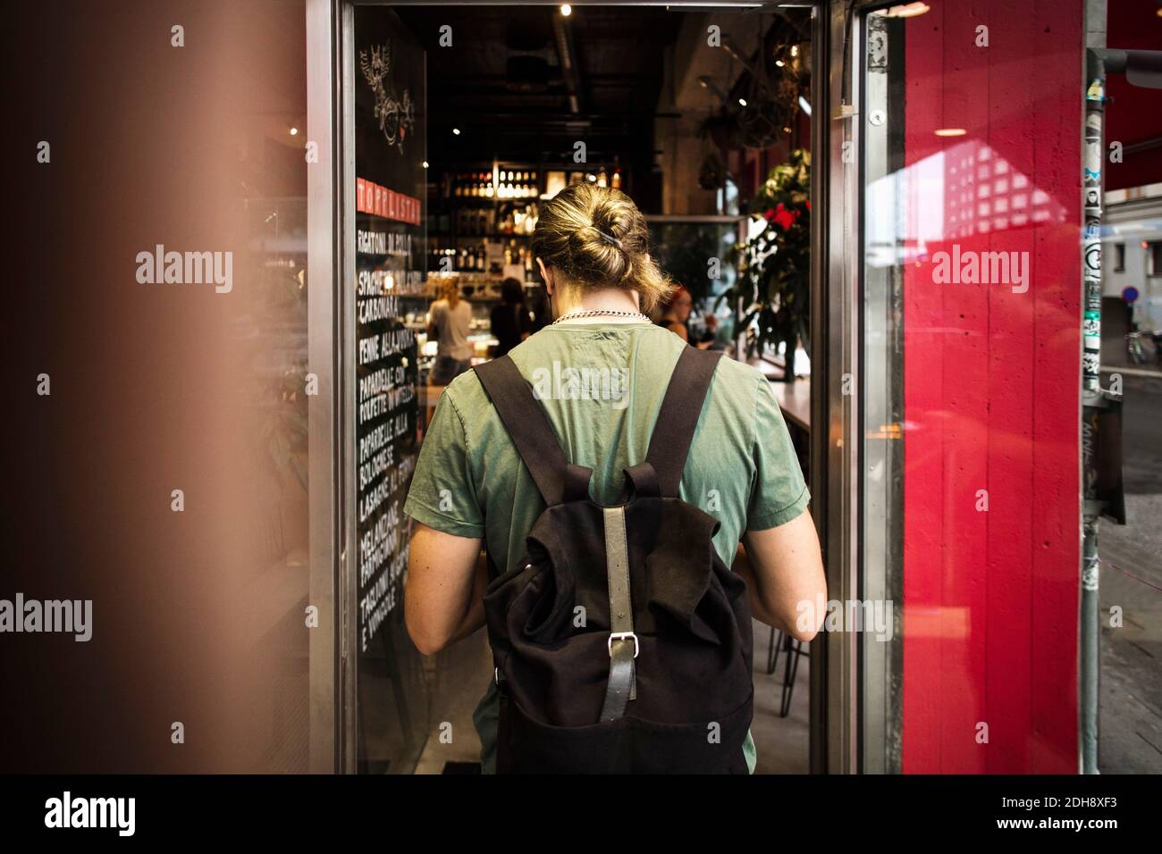 Rear view of man carrying backpack entering in restaurant Stock Photo ...