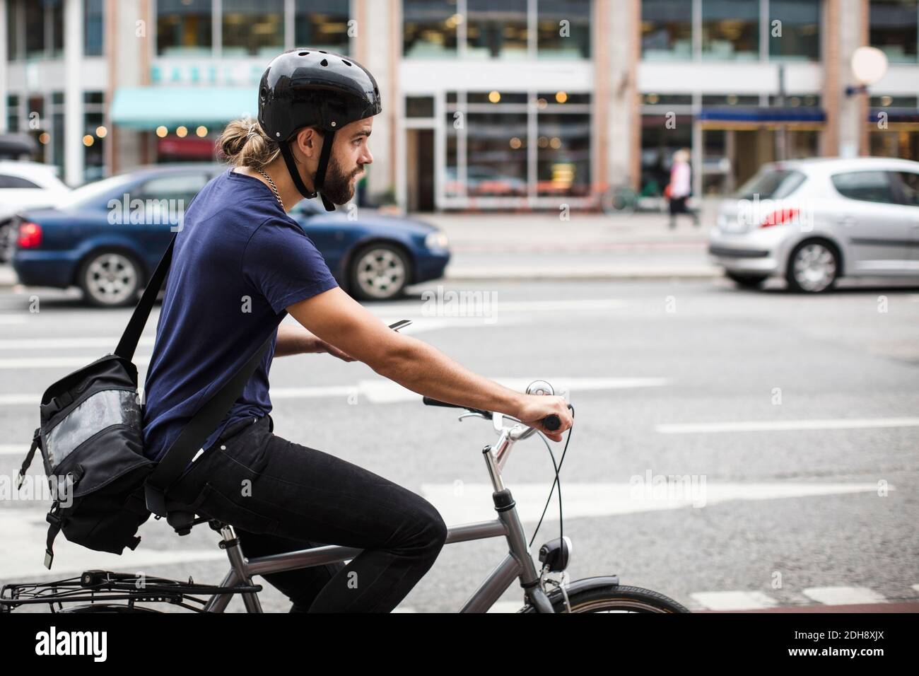 Side view of man cycling on city street Stock Photo - Alamy