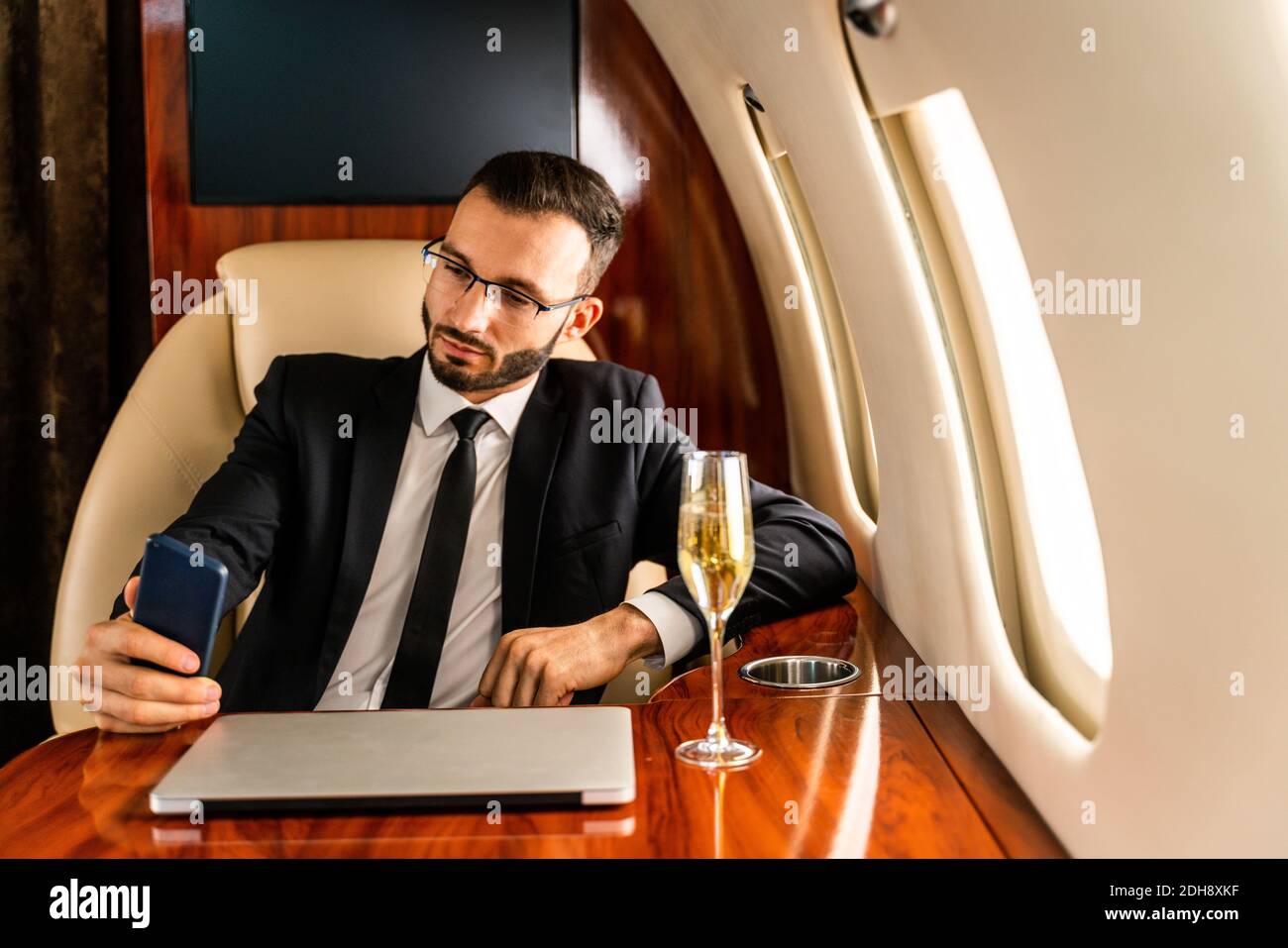 Handsome businessman wearing elegant suit flying on exclusive private ...