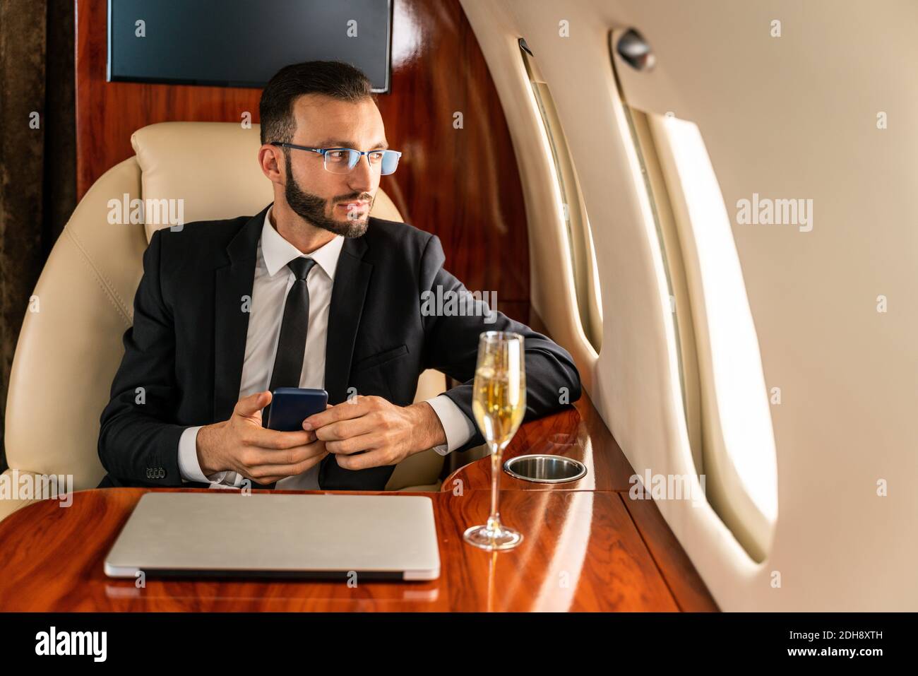 Handsome businessman wearing elegant suit flying on exclusive private ...