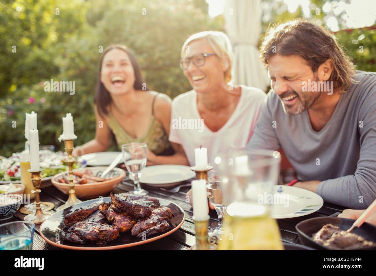 Cheerful couple and female friend laughing on dining table during ...