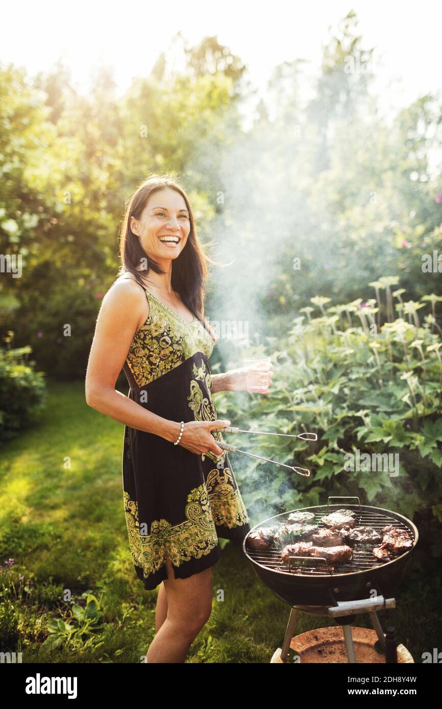 Happy woman standing by barbecue in back yard Stock Photo - Alamy