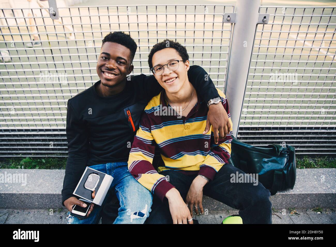 Portrait of smiling young men sitting against net Stock Photo - Alamy
