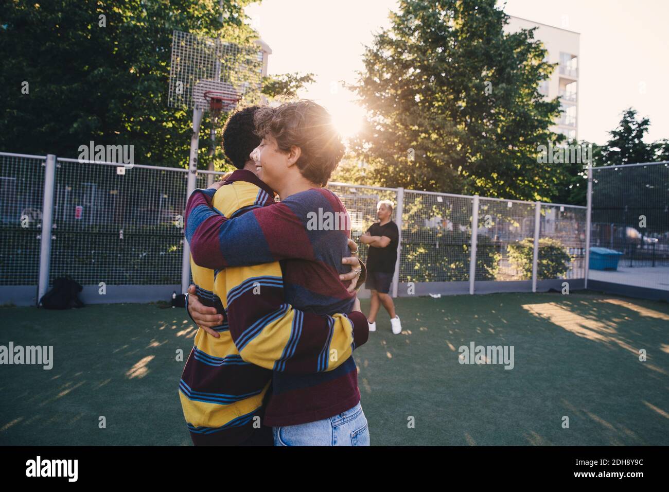 Male friends embracing each other while standing in field Stock Photo ...