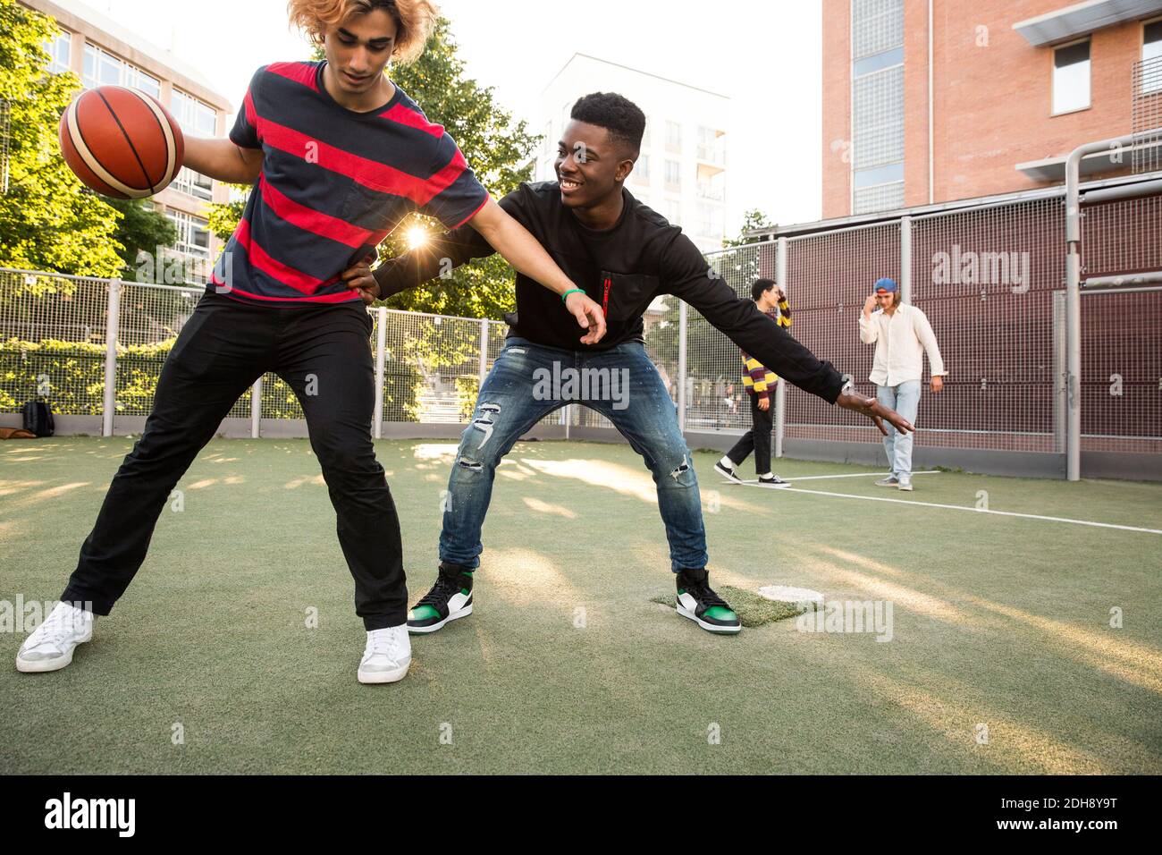 Young man taking basketball from male friend while playing in sports ...