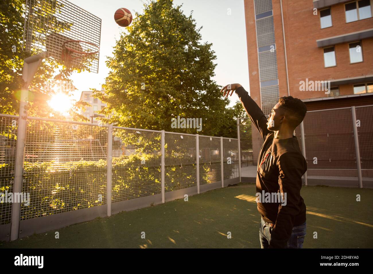 Side view of young man playing basketball in sports field Stock Photo ...