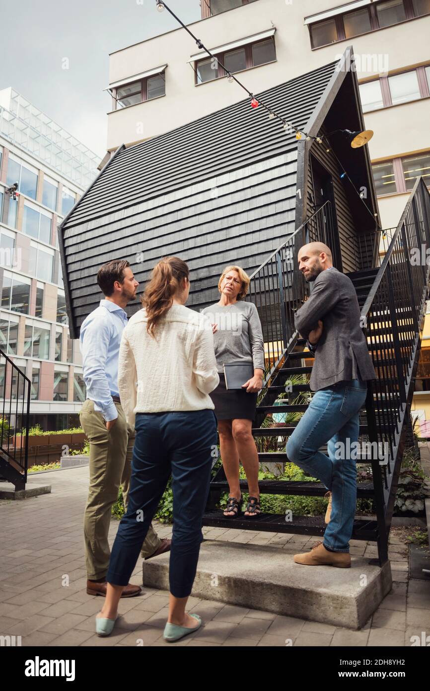 Business people discussing outside log cabin at office yard Stock Photo ...