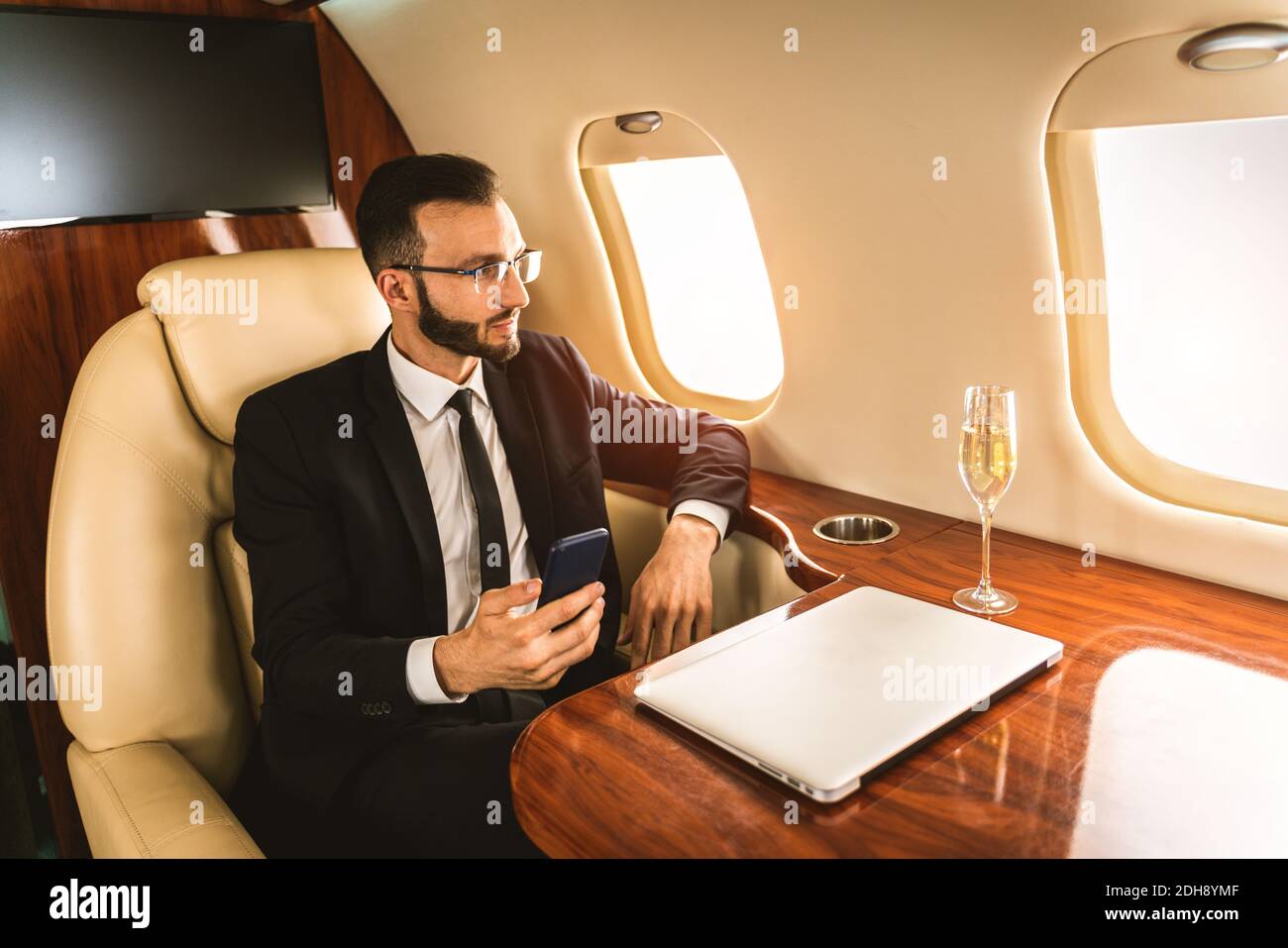 Handsome businessman wearing elegant suit flying on exclusive private ...