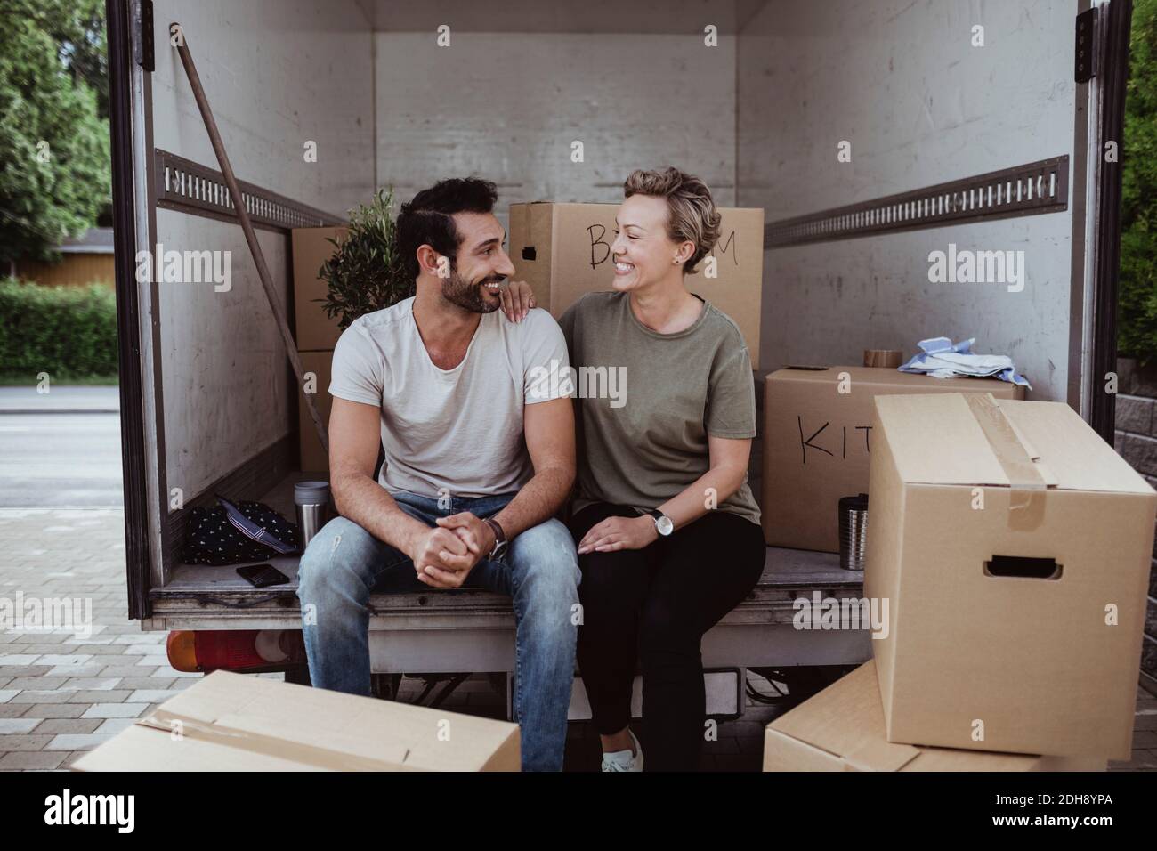 Smiling male and female partners looking at each other while sitting by ...