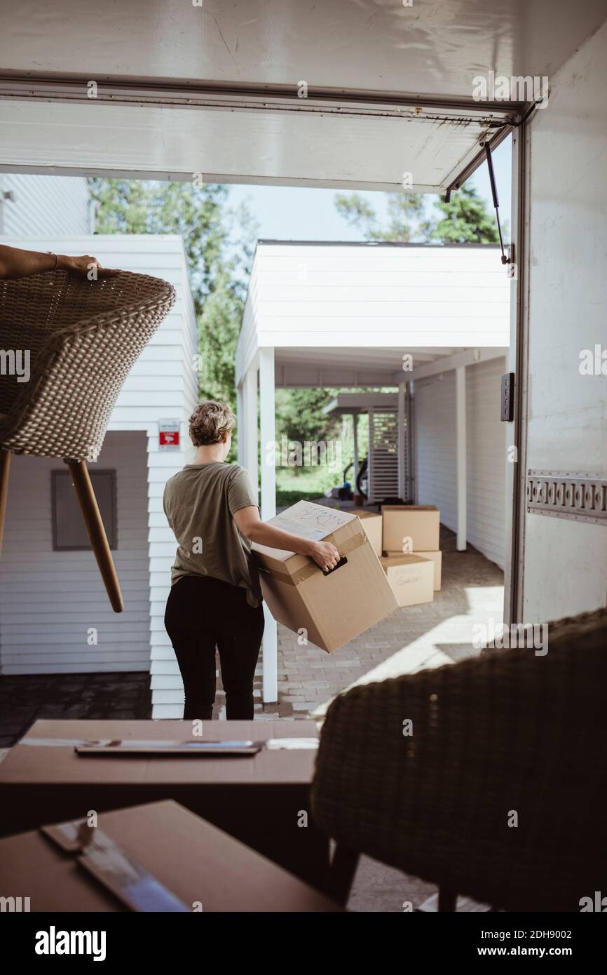 Female carrying cardboard box during relocation Stock Photo - Alamy