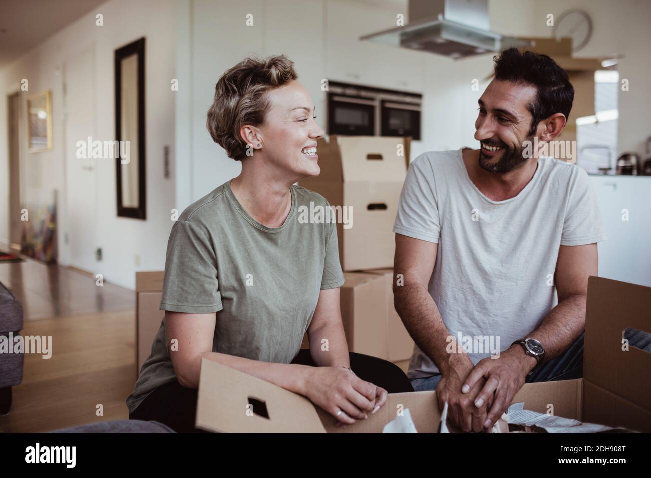 Smiling male and female partners looking at each other while unpacking ...
