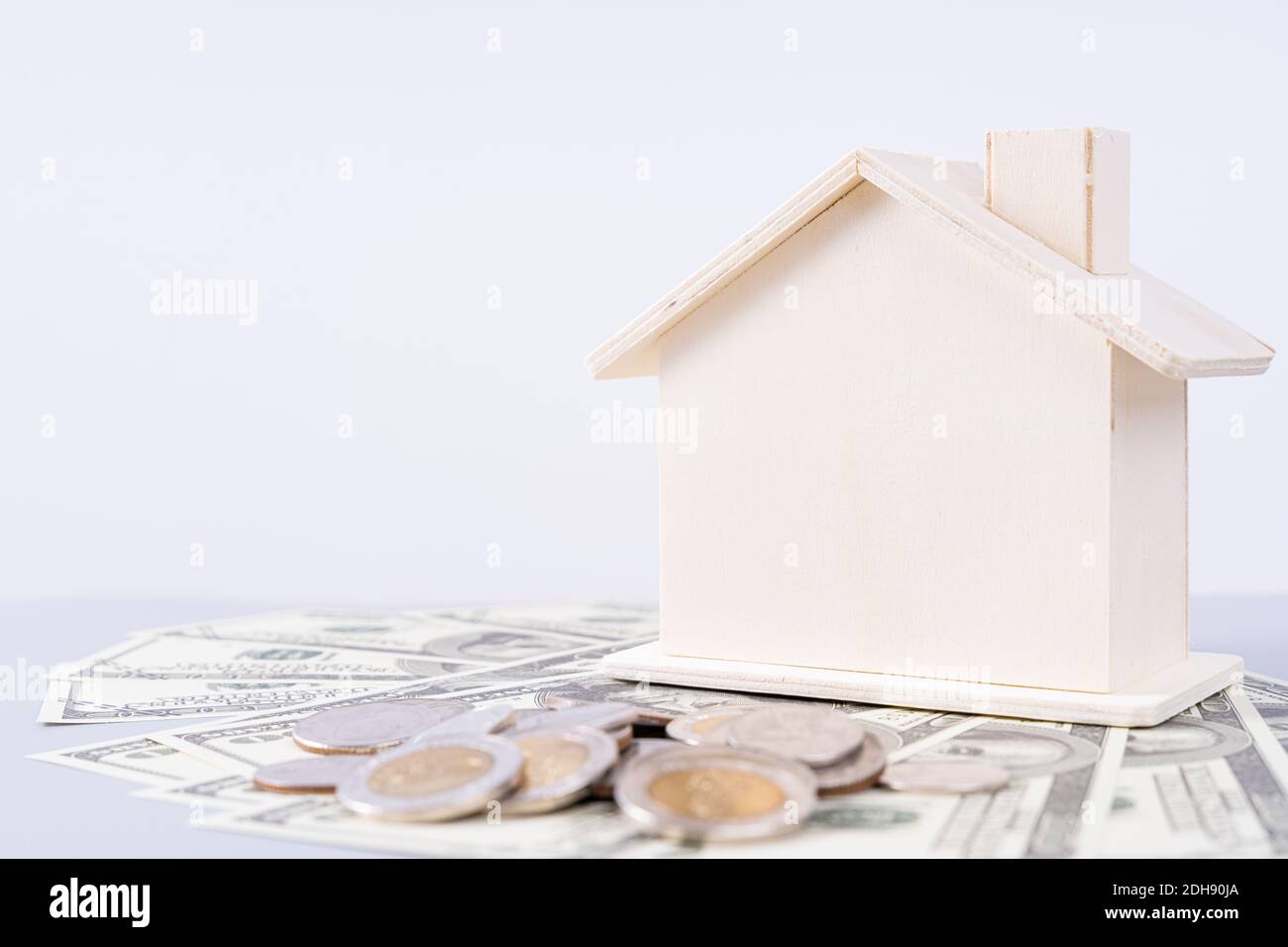 Wooden house and a pile of money coins and paper isolated grey ...