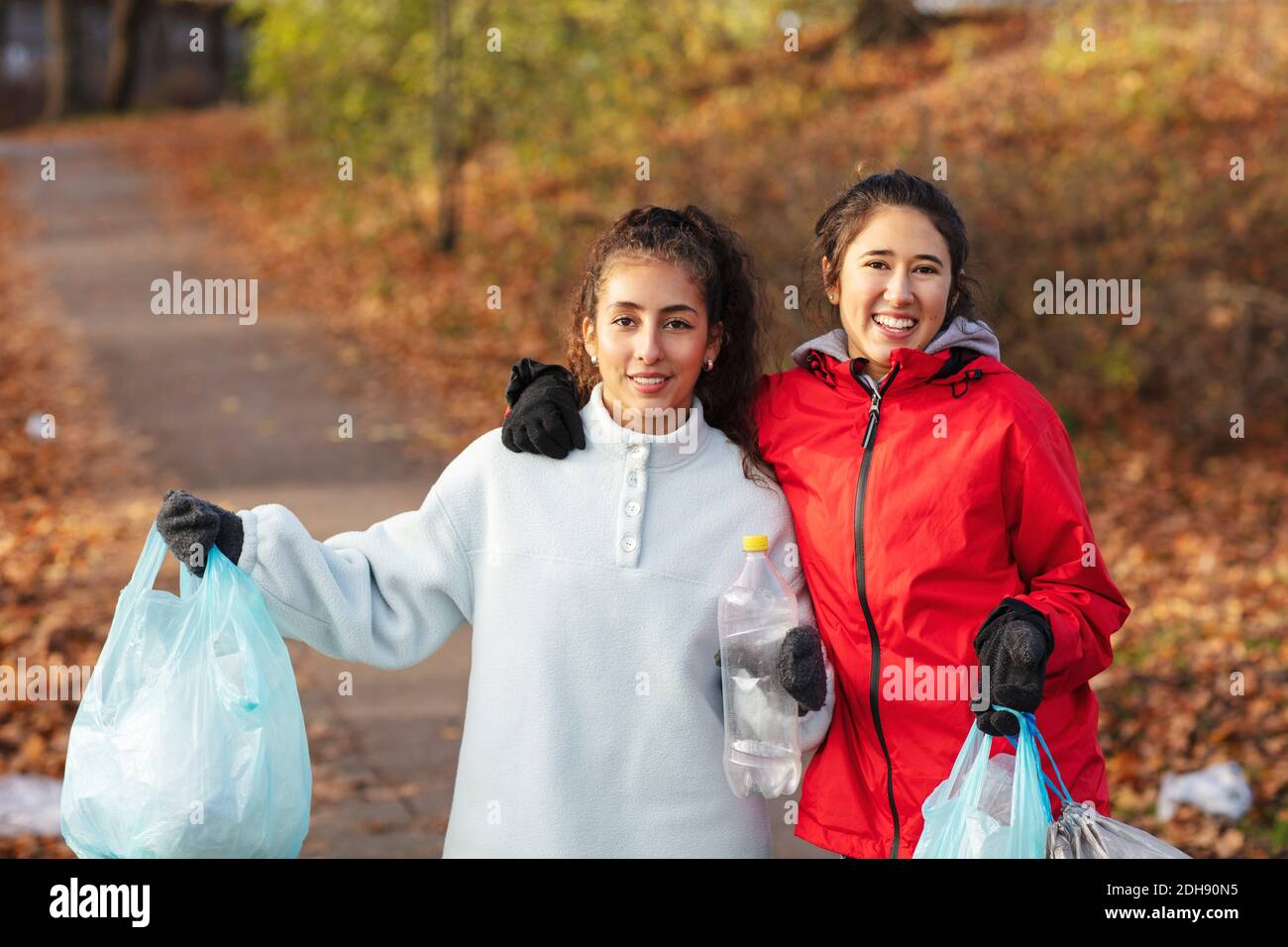 Portrait of female environmentalists holding plastic waste in park ...