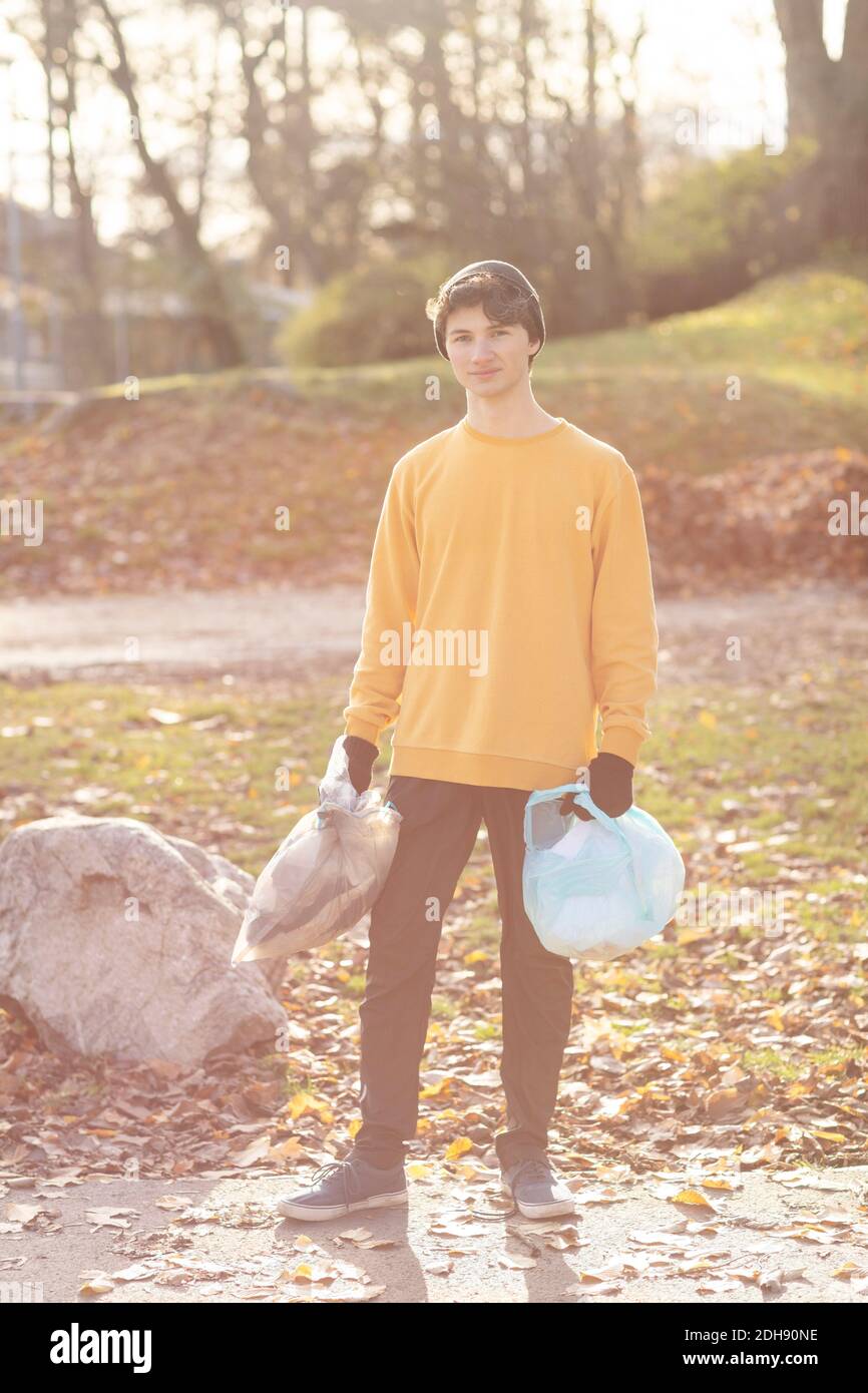 Portrait of male volunteer collecting garbage while standing in park ...