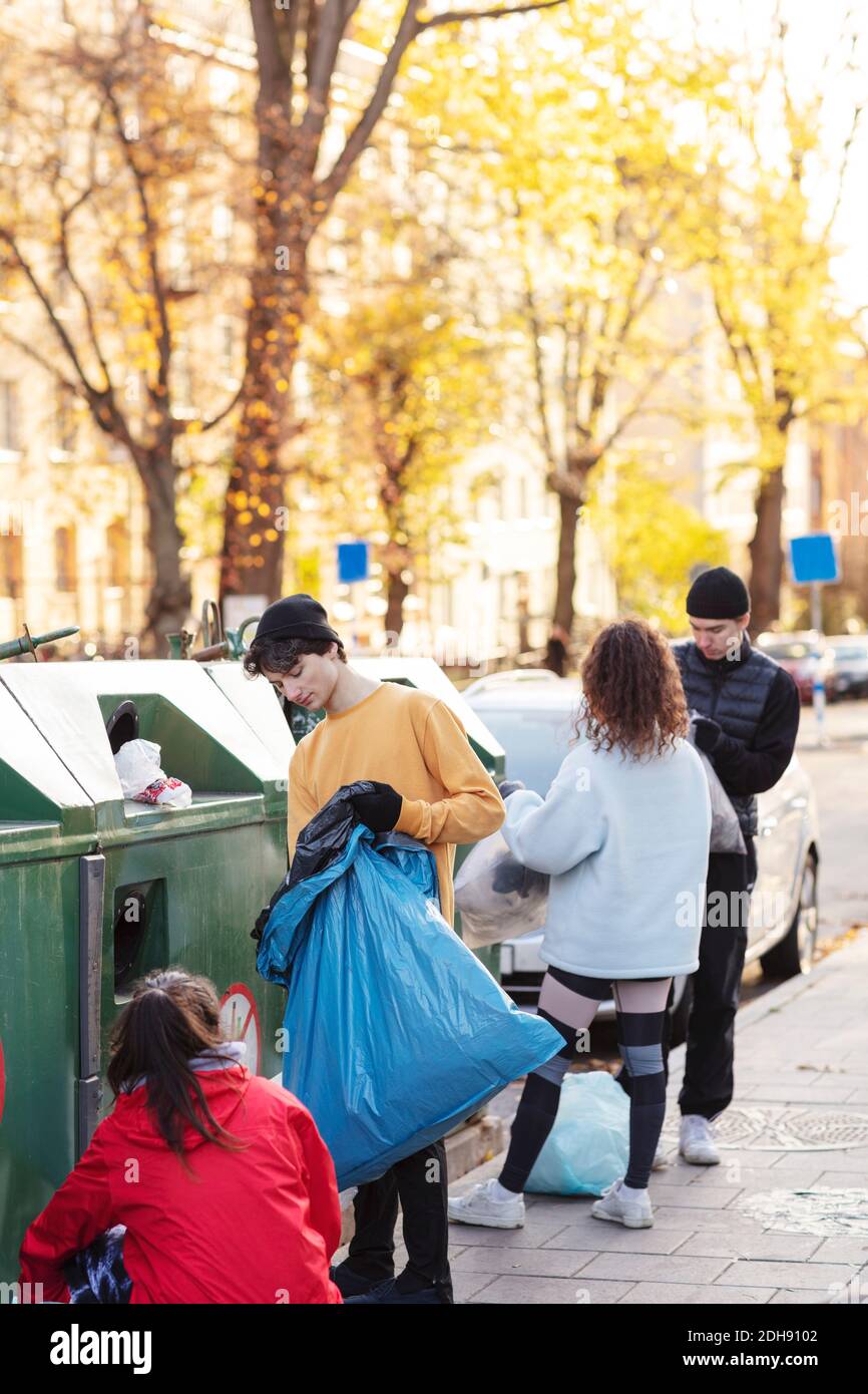 Young male and female environmentalists throwing plastic waste in ...