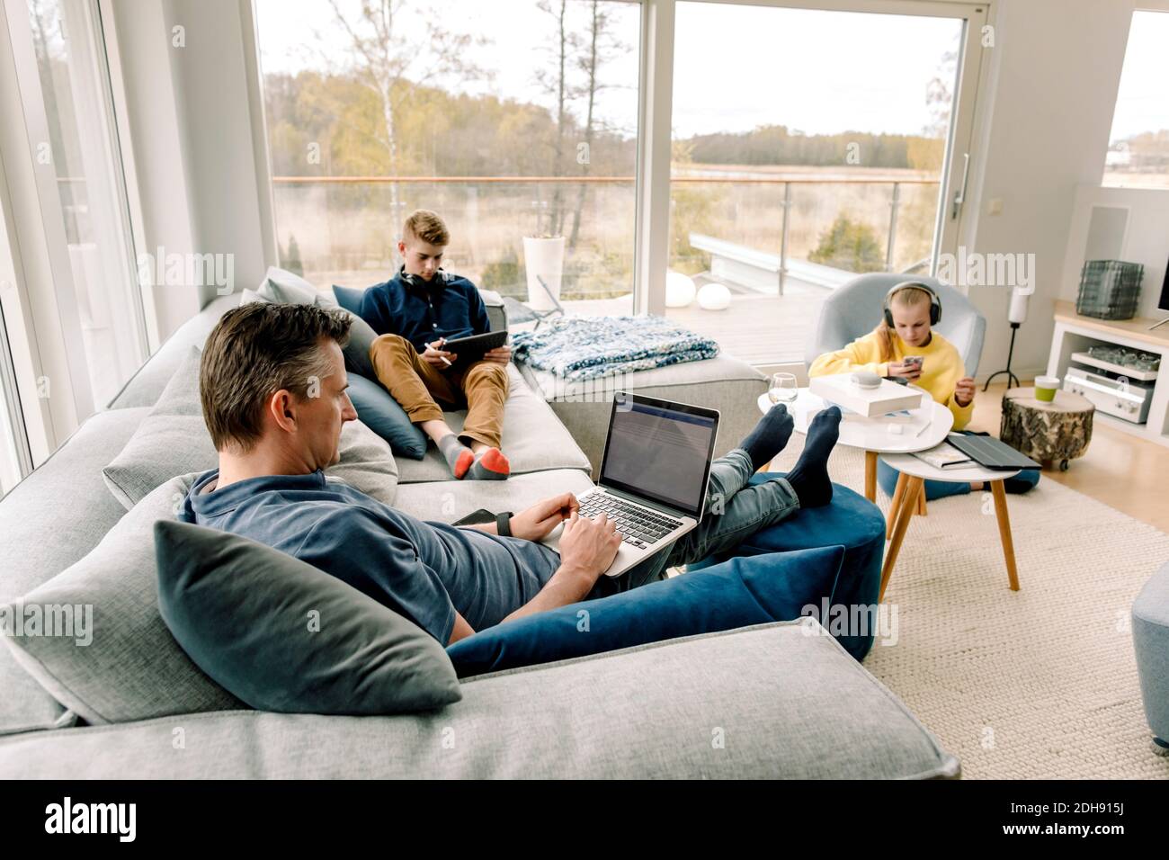High angle view of father and children using wireless technology at ...