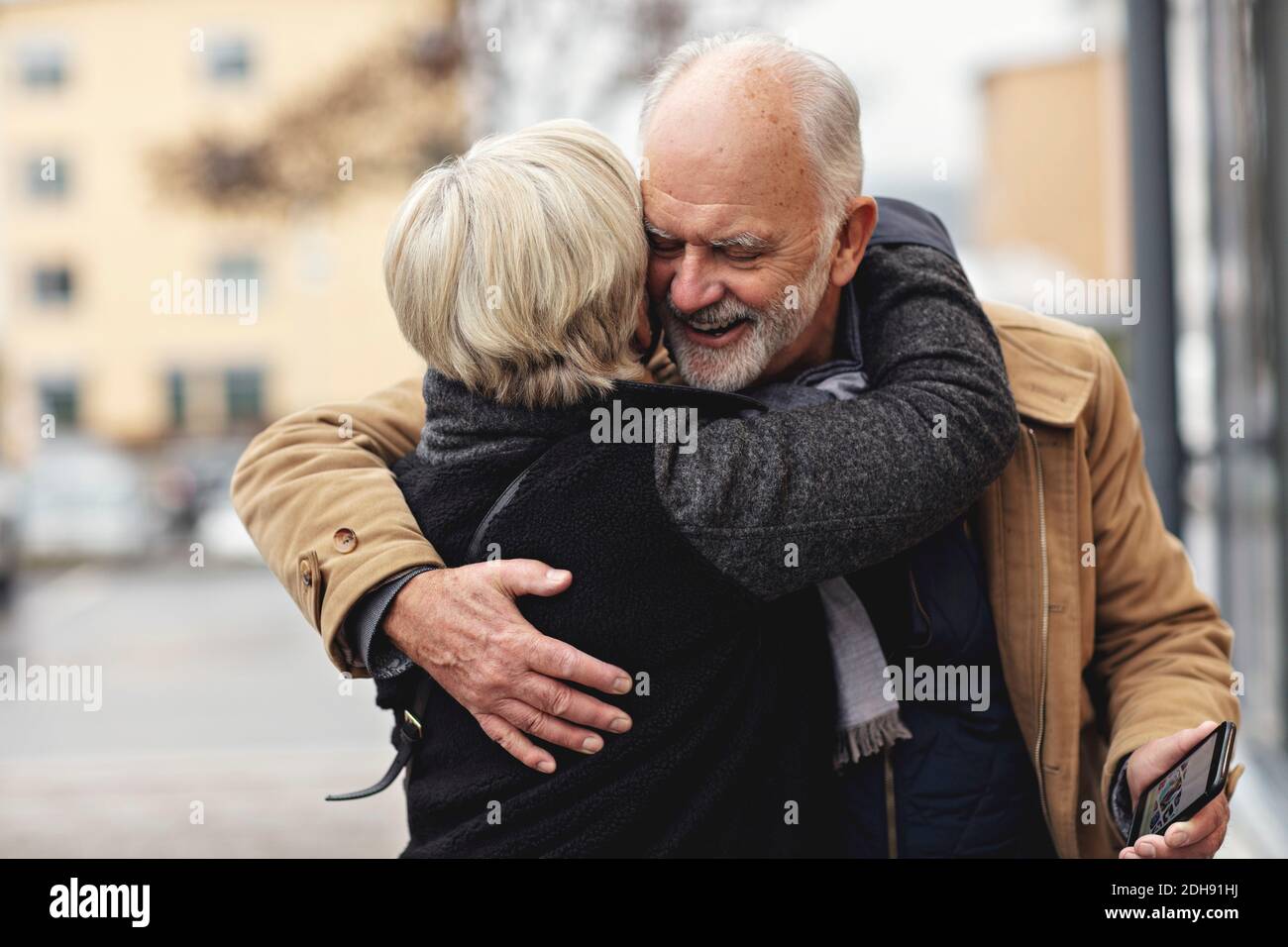 Smiling senior man embracing partner during winter in city Stock Photo ...