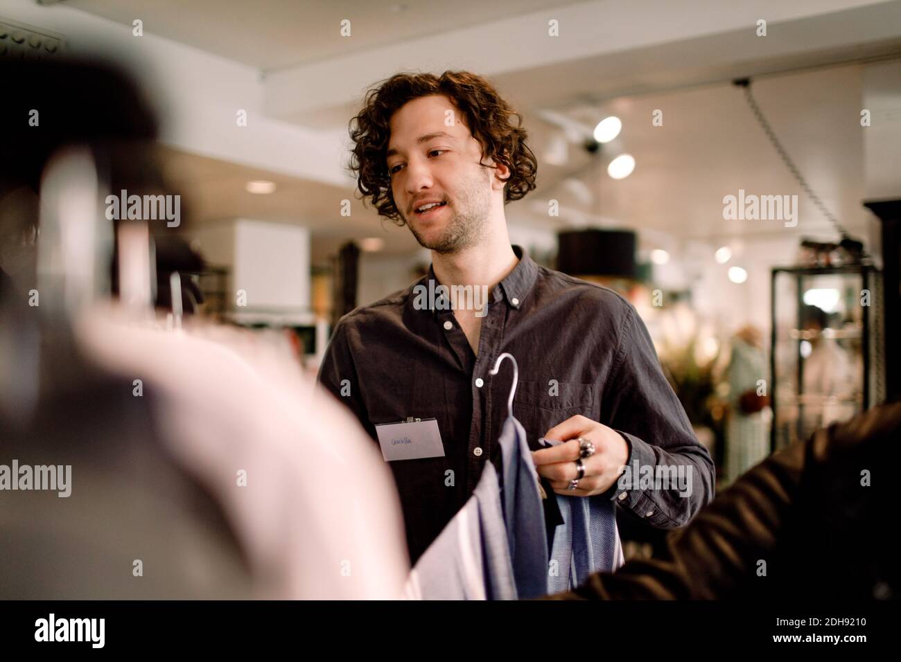 Salesman with clothes at fashion store Stock Photo - Alamy
