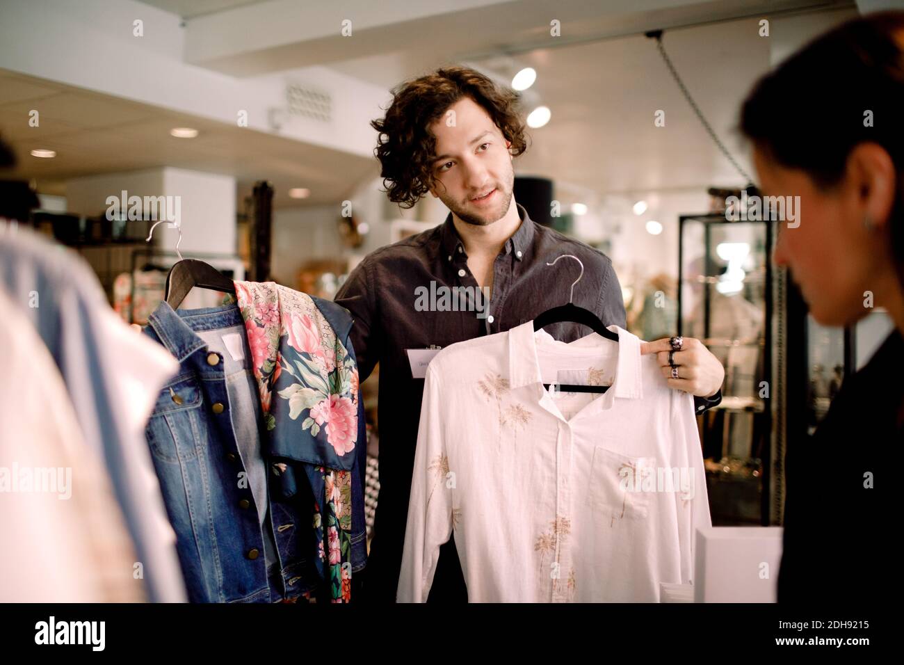 Salesman showing clothes to customer at store Stock Photo - Alamy
