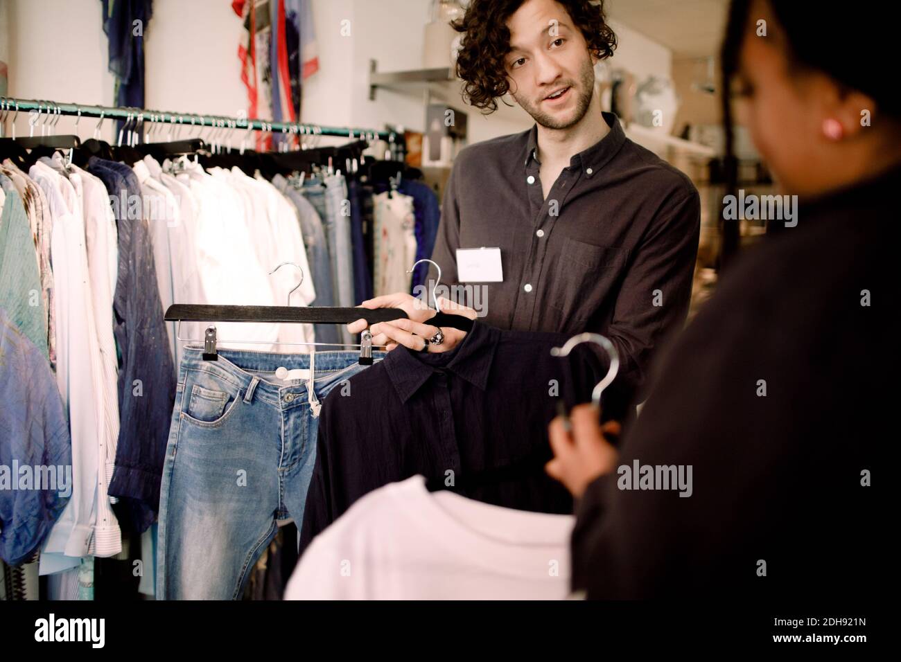 Salesman showing fashionable clothing to customer in store Stock Photo ...