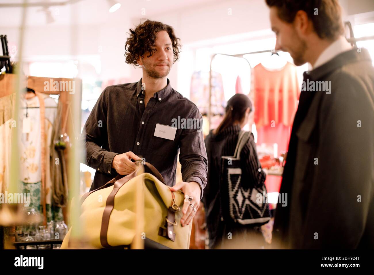 Salesman showing luggage bag to male customer at store Stock Photo - Alamy