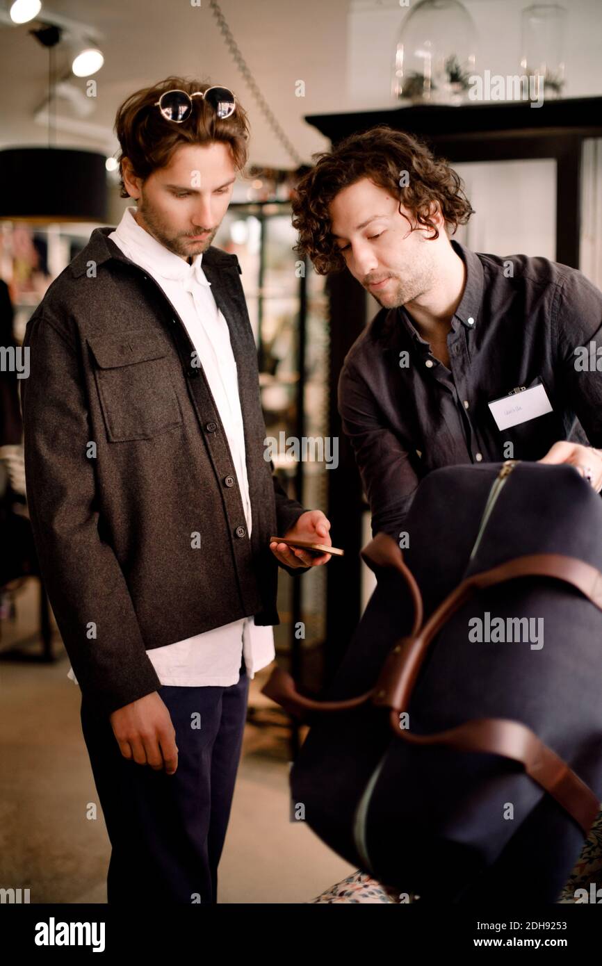 Salesman showing luggage bag to customer at retail store Stock Photo ...