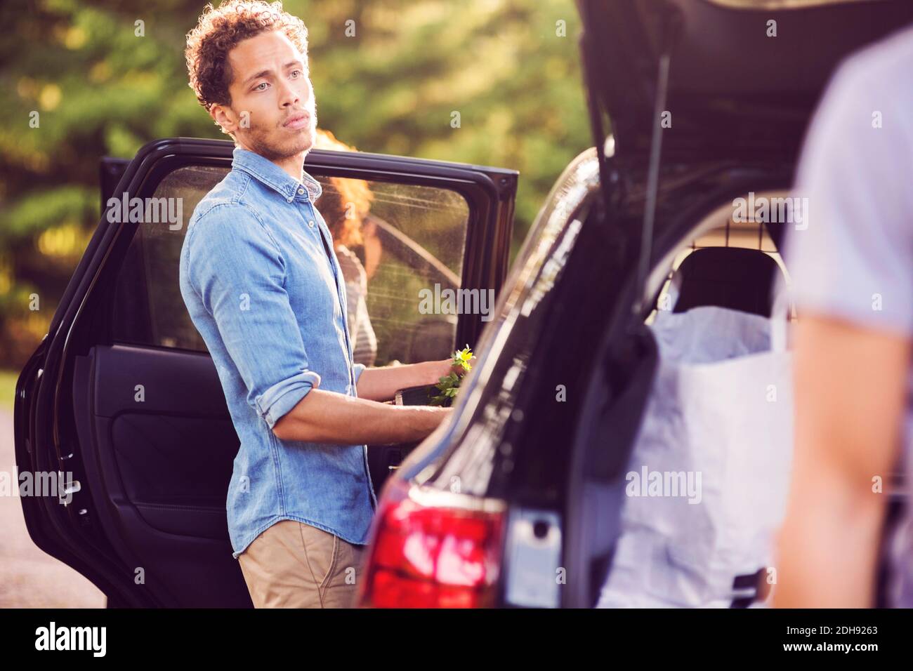 Friends loading luggage into car on sunny day Stock Photo - Alamy
