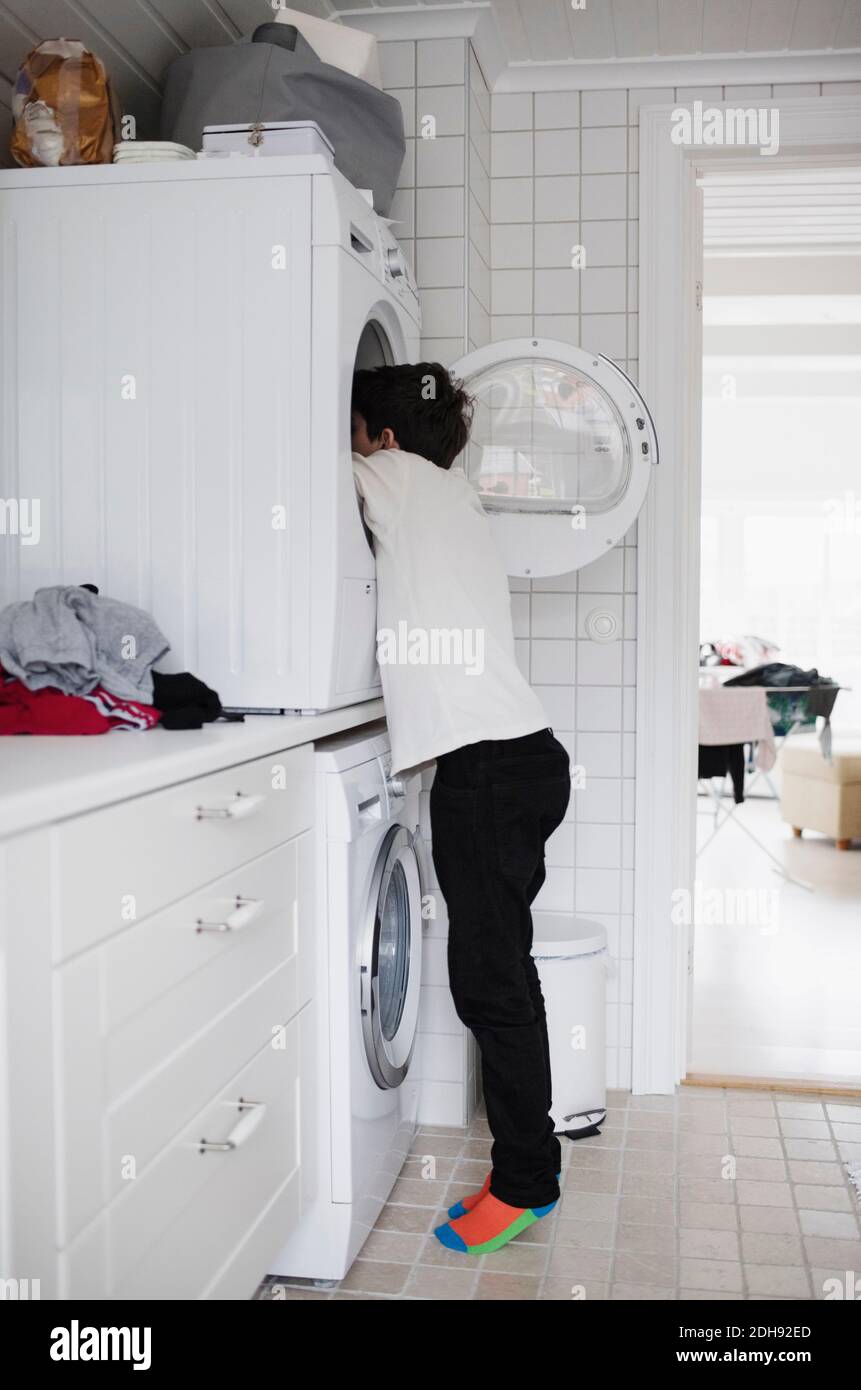 Side view of boy loading clothes in washing machine at home Stock Photo ...